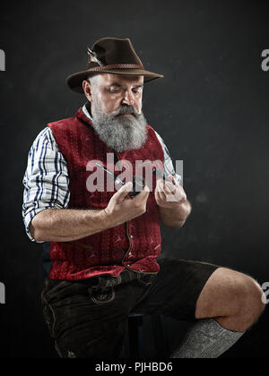 Man in Tyrolean hat with feather and leather shorts on white background ...