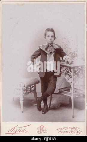 Young boy wearing Victorian clothes and an old fashioned cloth flat cap ...