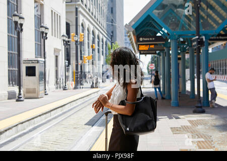Businesswoman checking time by light rail line Stock Photo - Alamy