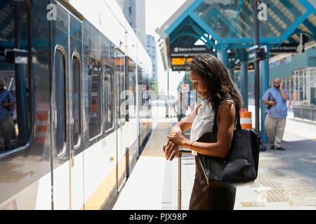 Businesswoman checking time by light rail line Stock Photo - Alamy