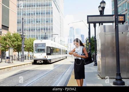 Businesswoman checking time by light rail line Stock Photo - Alamy