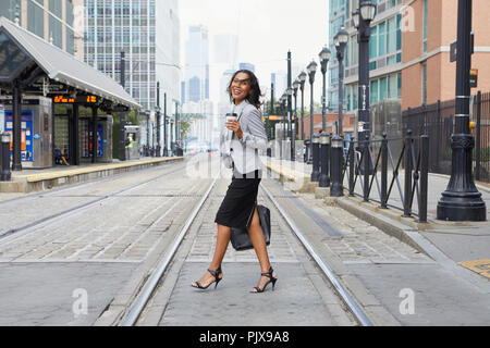 Businesswoman crossing light rail tracks Stock Photo - Alamy