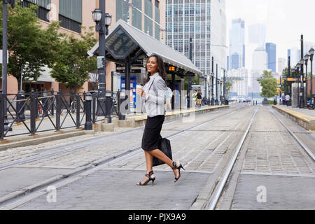 Businesswoman crossing light rail tracks Stock Photo - Alamy