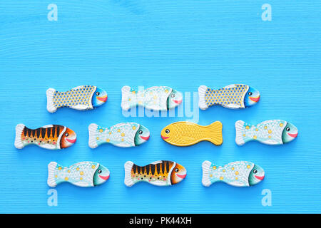 one fish swimming the opposite way the rest of the school is toned with ...