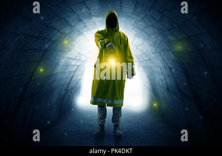 Ugly man in raincoat walking with glowing lantern in a dark tunnel ...