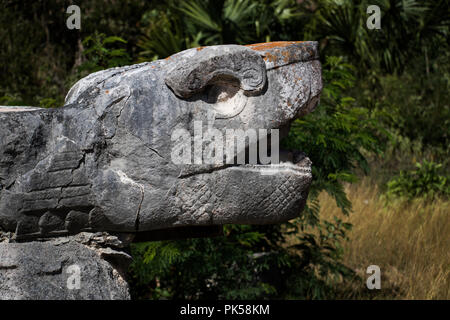 Mayan stone snake head sculpture with the pyramid of Kukulcan in the ...