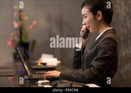 Hotel Receptionist Using Computer And Phone Stock Photo - Alamy