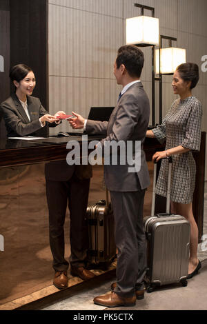 Asian hotel staff checking passport for id at check in, does ...