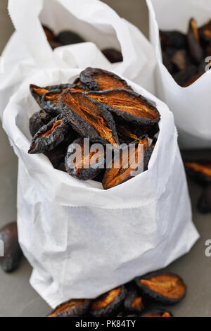 Several organic black plums on a round wooden tray, close-up, on a ...