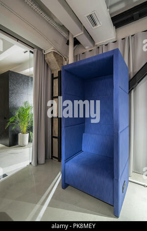 Relax zone in the coworking in a loft style with large windows and gray ...