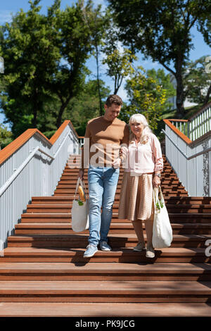 Young man helping elderly woman onto pavement - France Stock Photo - Alamy