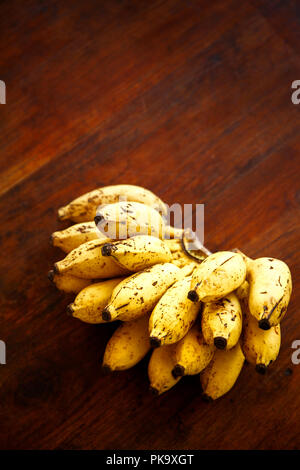 A bunch of little ripe bananas on a blue concrete background Stock ...