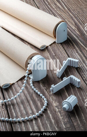 The rolled beige shutters is on a wooden surface. Beige blinds lie on ...