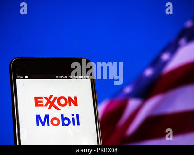The Exxon Mobil logo displayed on a phone screen against a world map ...