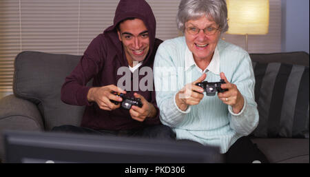 Mature hispanic woman playing video games at home sticking tongue out ...