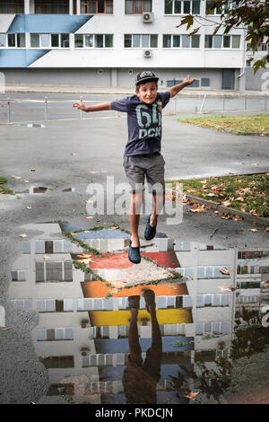 Boy jumps in a puddle in the street after a rainy day Stock Photo - Alamy
