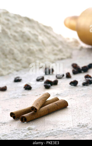Cinnamon sticks with wheat flour,raisins and rolling pin on a wooden ...