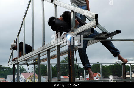 Asian male welder is welding steel beams in process of home renovation ...