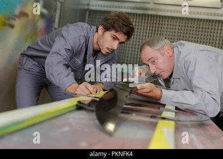 Two positive workmen toiling at the locksmiths workshop and smiling ...