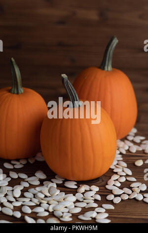 Fresh orange pumpkins and pimpkin seeds in a bowl close-up on wooden ...
