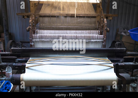 Vietnamese woman operates a silk weaving machine in the silk factory in ...