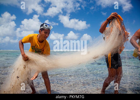Locals prepare a fishing net to catch fish in the lagoon at Lepa Beach ...