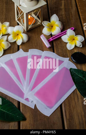 Pink cold wax strips with pink razor blade on wooden surface with ...