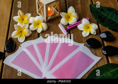 Pink cold wax strips with pink razor blade on wooden surface with ...