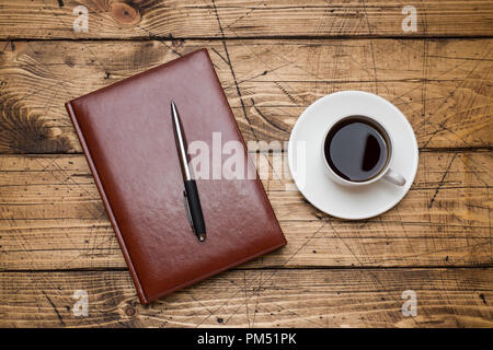 Diary in leather cover and Cup of coffee on wooden background ...