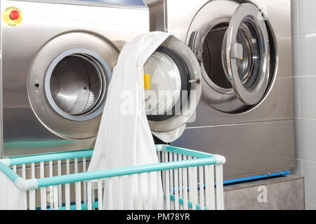 Washing machine overloaded with clothes and empty basket in laundry ...