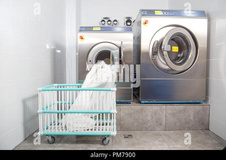 Washing machine overloaded with clothes and empty basket in laundry ...