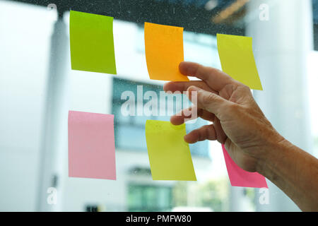 hand hold adhesive notes on glass wall at workplace. Sticky note paper ...