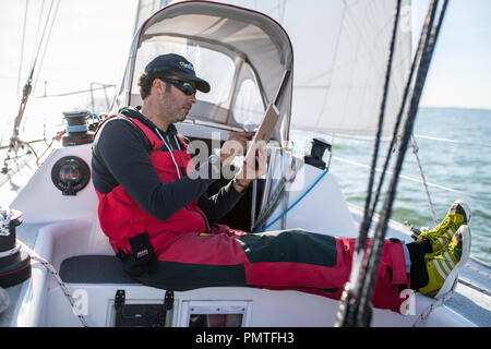 Sailor looking on an ipad while sailing. For navigation and weather ...