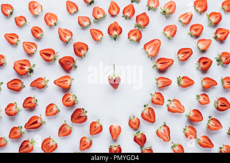 top view of round frame of halved strawberries with whole in middle on ...
