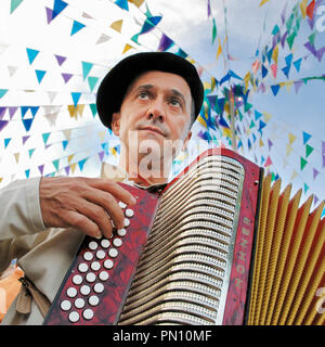 A one man band playing a concertina or small accordion,cymbals, bass ...