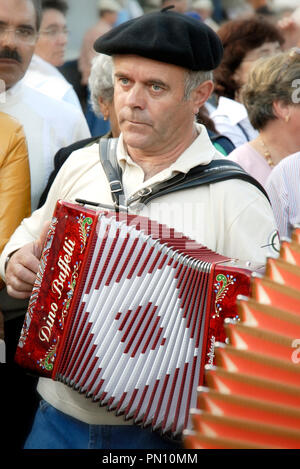 A one man band playing a concertina or small accordion,cymbals, bass ...