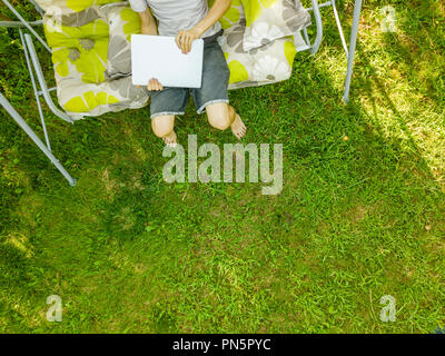 Top view of unrecognizable male freelancer sitting at poolside with ...