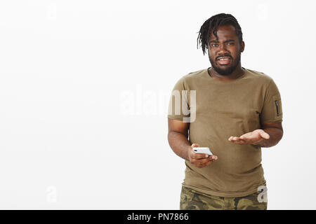 displeased african american man messaging smartphone on orange ...