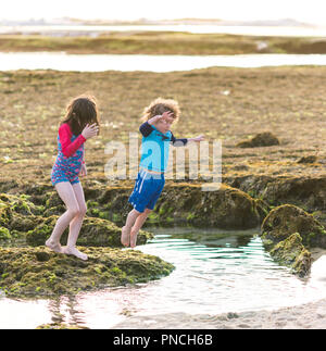 Children playing in rock pools at Coles Bay, with the Hazards mountains ...