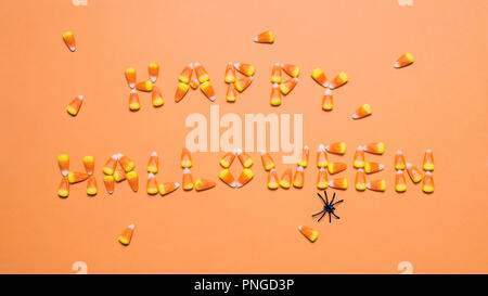 Candy corn spelling out the words Happy Halloween with plastic spiders ...