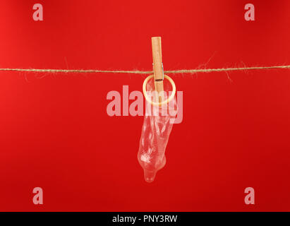 Close up one condom hanging on twine washing line with wooden ...
