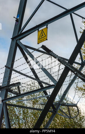 Steel electricity pylon with warning sign against a cloudless clear ...