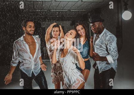 Group of friends dancing under the rain - Multiethnic people having ...