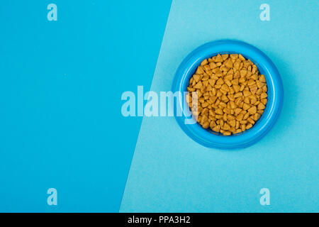 Blue food bowl with cat kibble seen from a high angle view on a blue ...