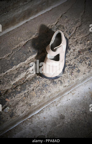 Single shoe abandoned on concrete symbolizing loss, loneliness, and ...