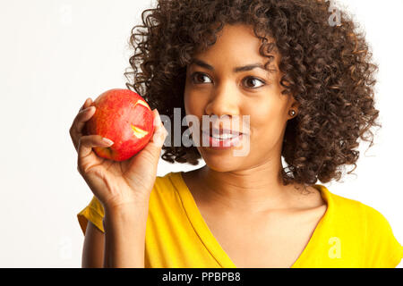 Portrait of millennial black woman taking bite of apple inside home ...