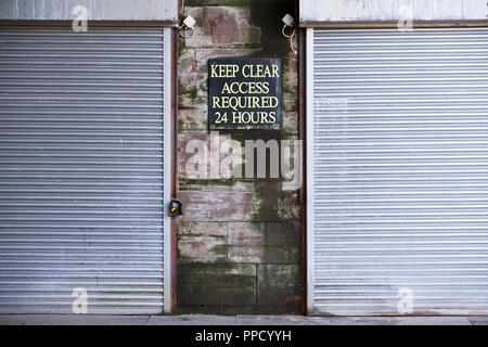 Keep clear 24 access required sign at business entrance roller shutter ...