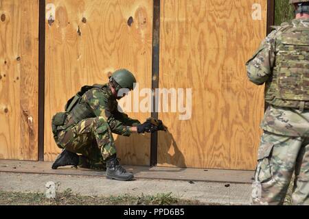 A Dutch Soldier uses an M500 shotgun to breach a door during the Urban ...