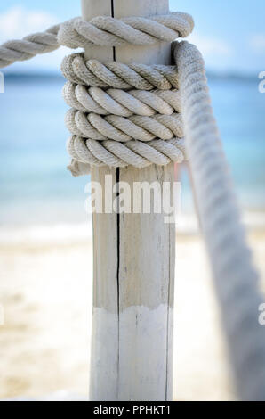 old rope wrapped around a pole that is surrounded by sand, beach Stock ...