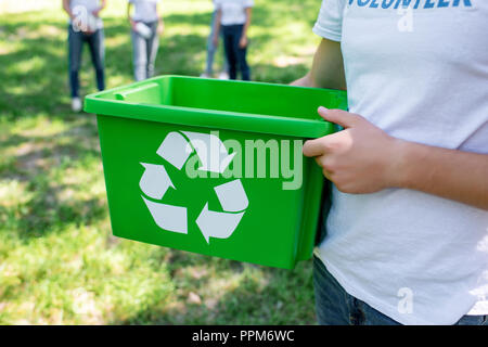 cropped view of volunteer holding green recycling box in park with ...
